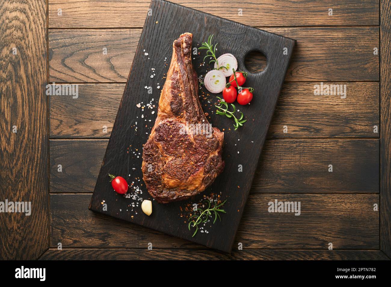 Tomahawk steak. Sliced grilled tomahawk beef steak with baked cherry ...