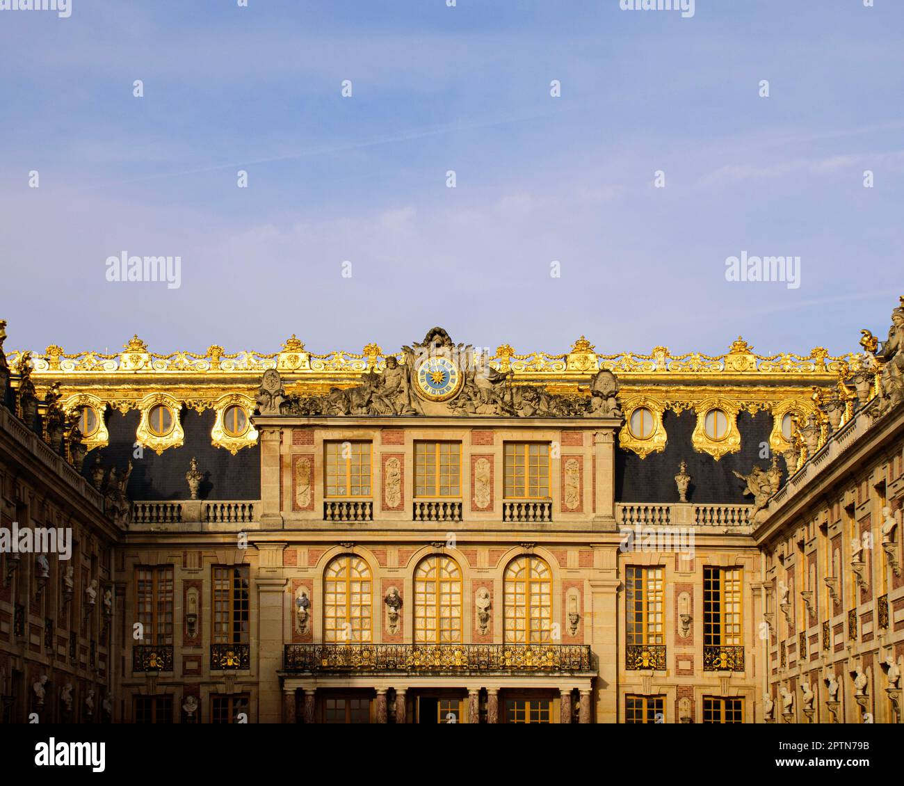 Entrance to the Palace of Versailles illuminated by the sun at dawn ...