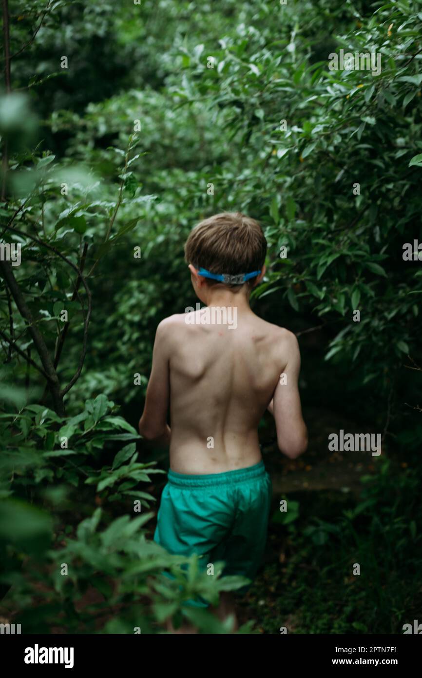 Shirtless boy hiking through jungle in summer Stock Photo - Alamy