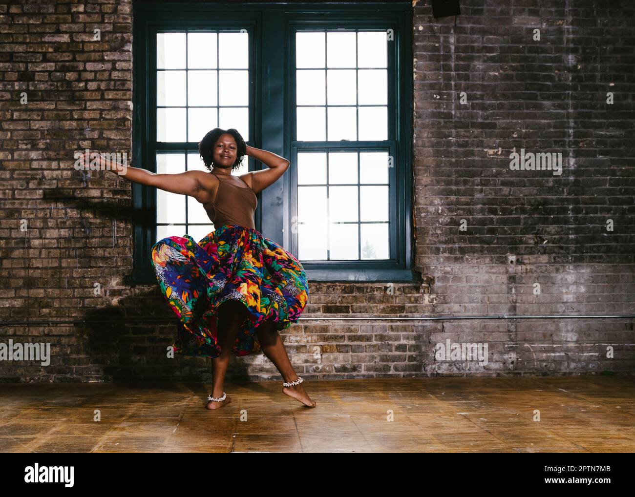 Black female dancer twirls in multi colored skirt by brick wall Stock ...