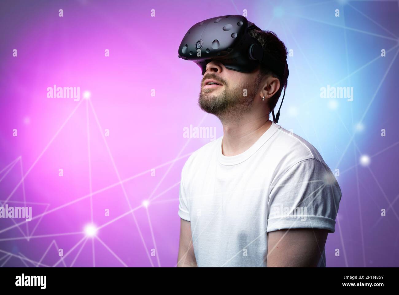 Guy in VR glasses of virtual reality over space gradient colorful background. Enjoying Modern ...