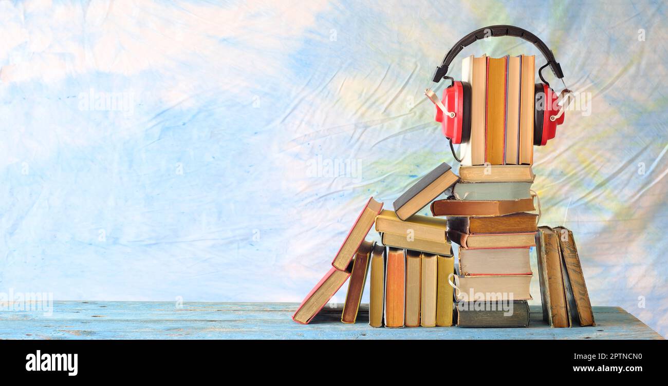 audio book concept with stack of books and vintage red headphone on ...