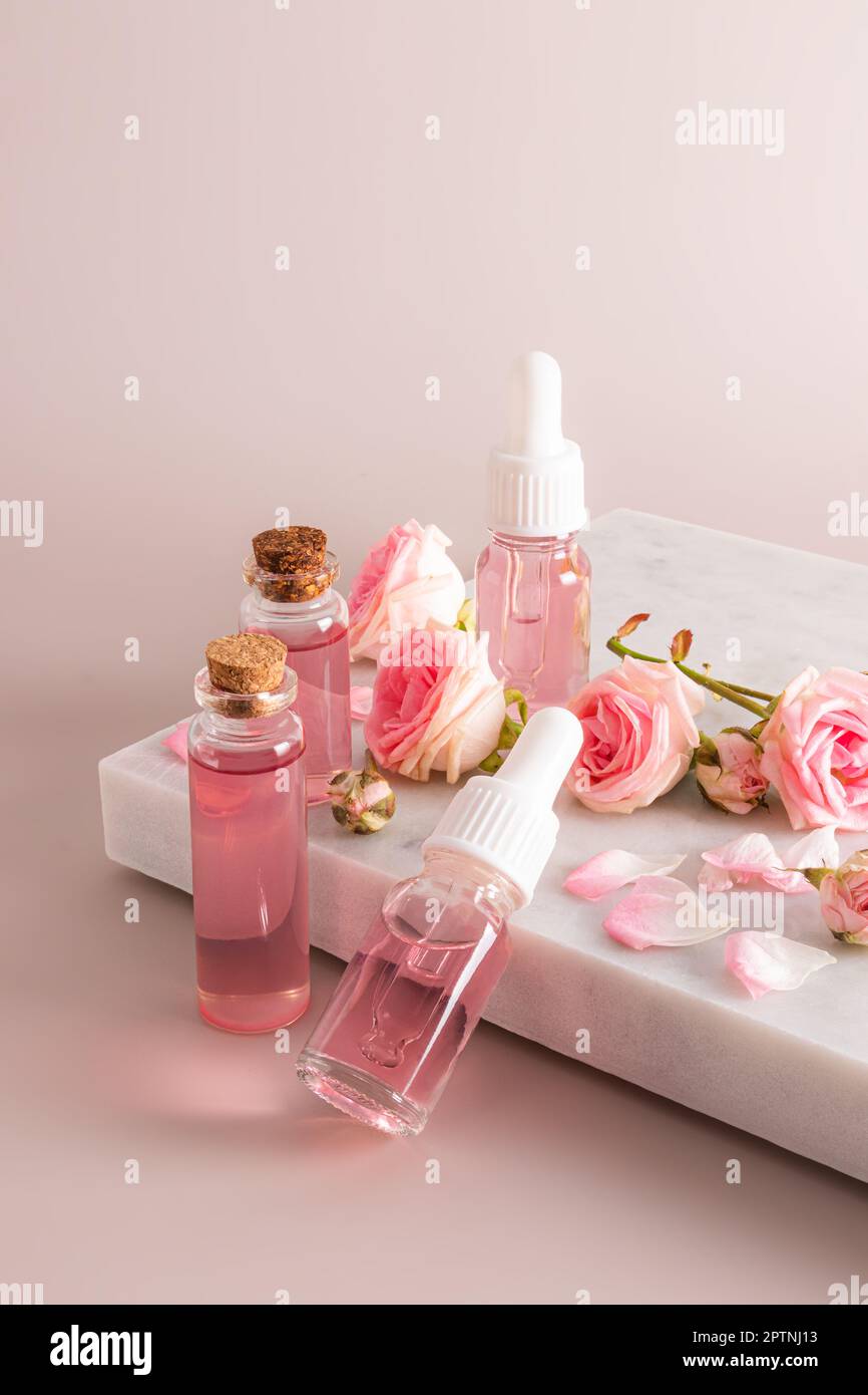 A set of cosmetics and rose water in glass bottles among small fresh ...