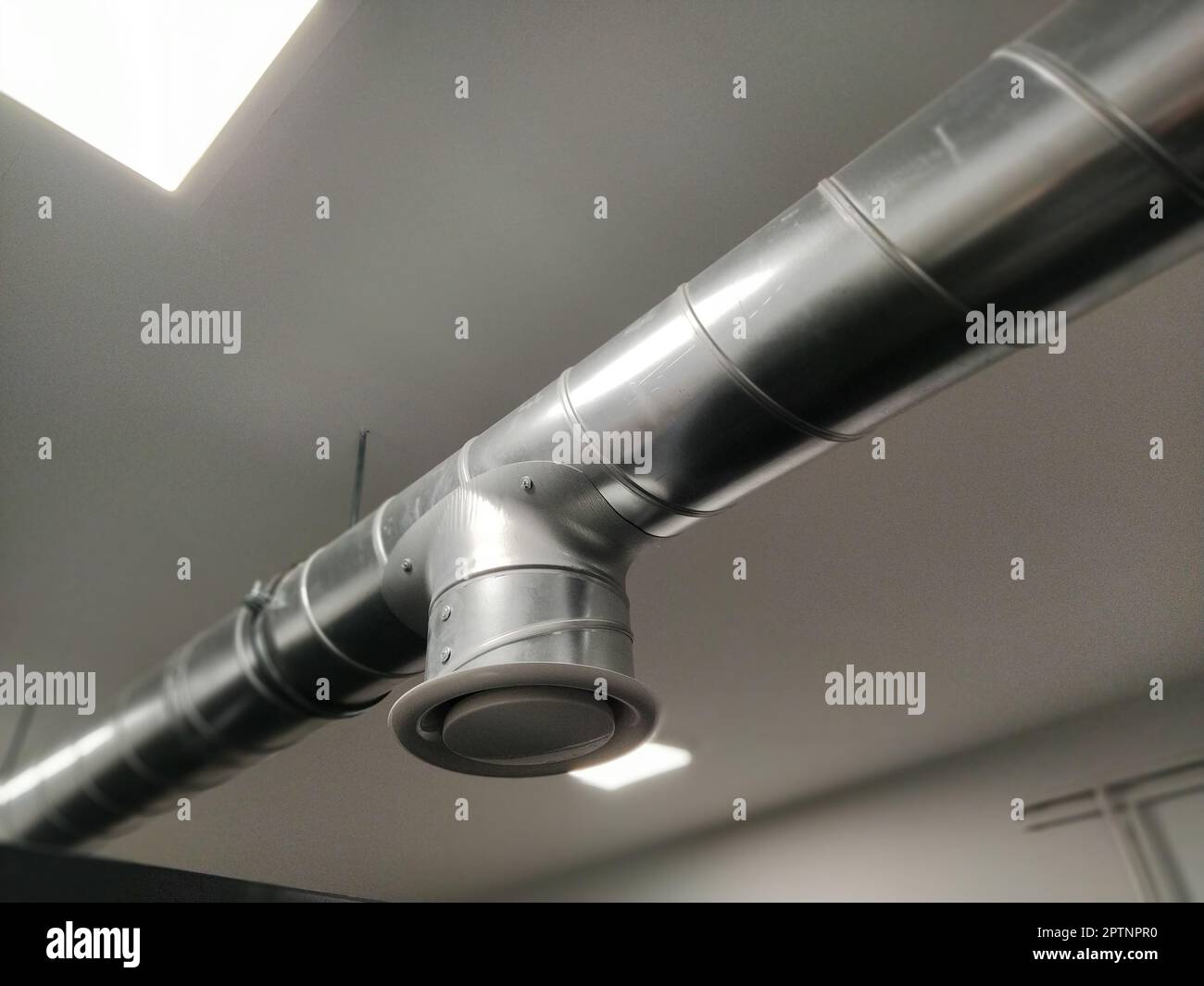 Extractor hood in a public toilet. Round metal pipe with gray air ...