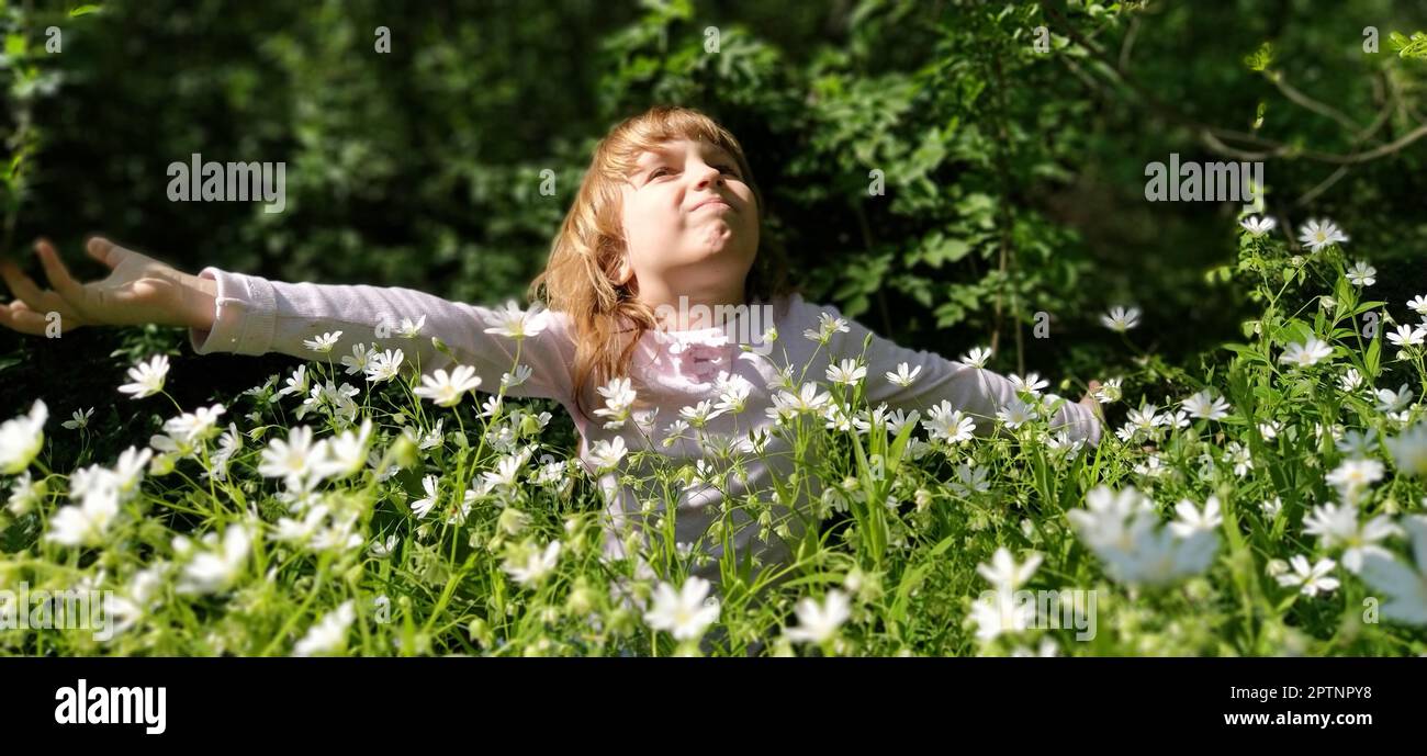 Cute girl with blond hair in the meadow. Wildflowers are white ...
