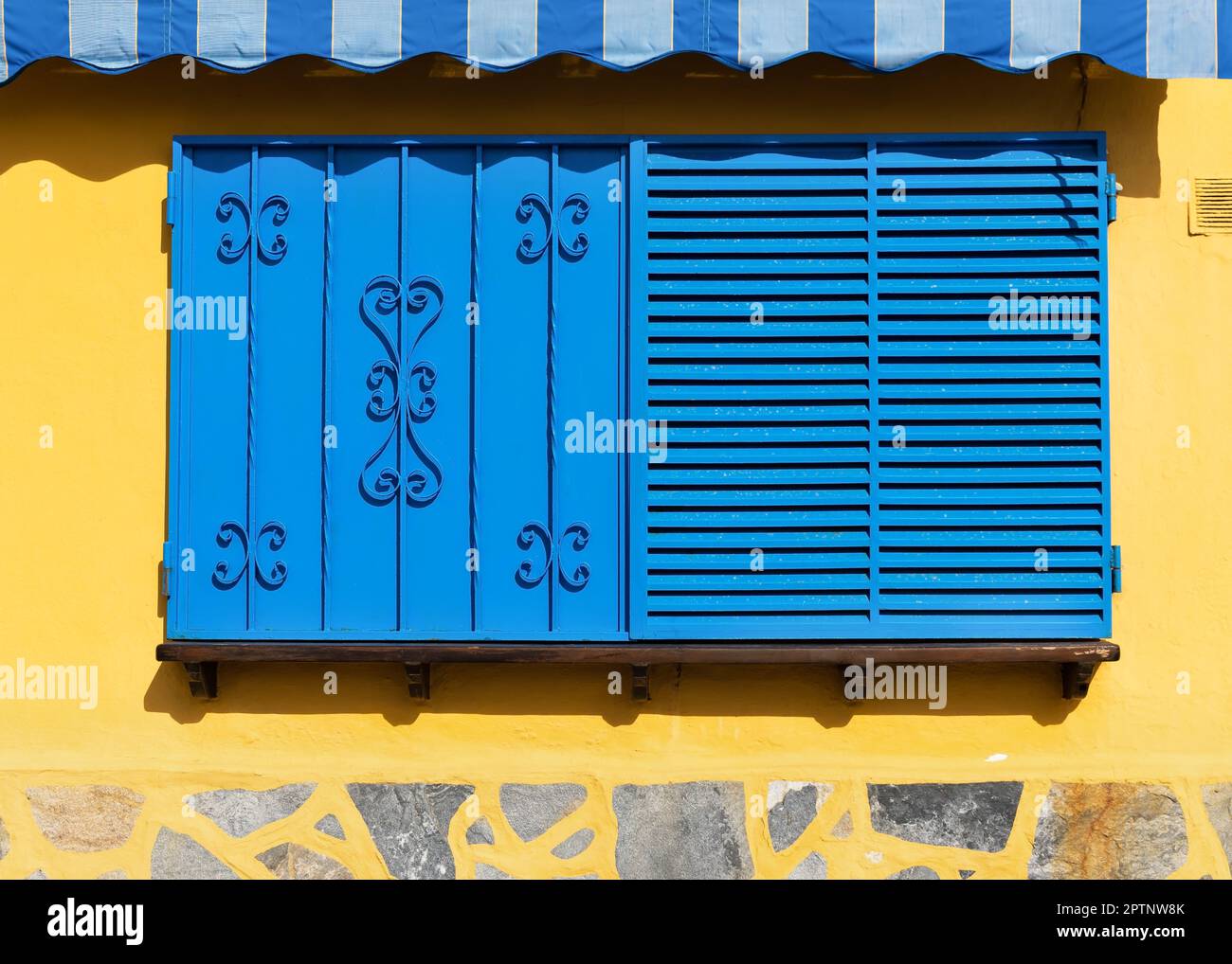 Architecture of an old yellow wall with an old blue metal window ...