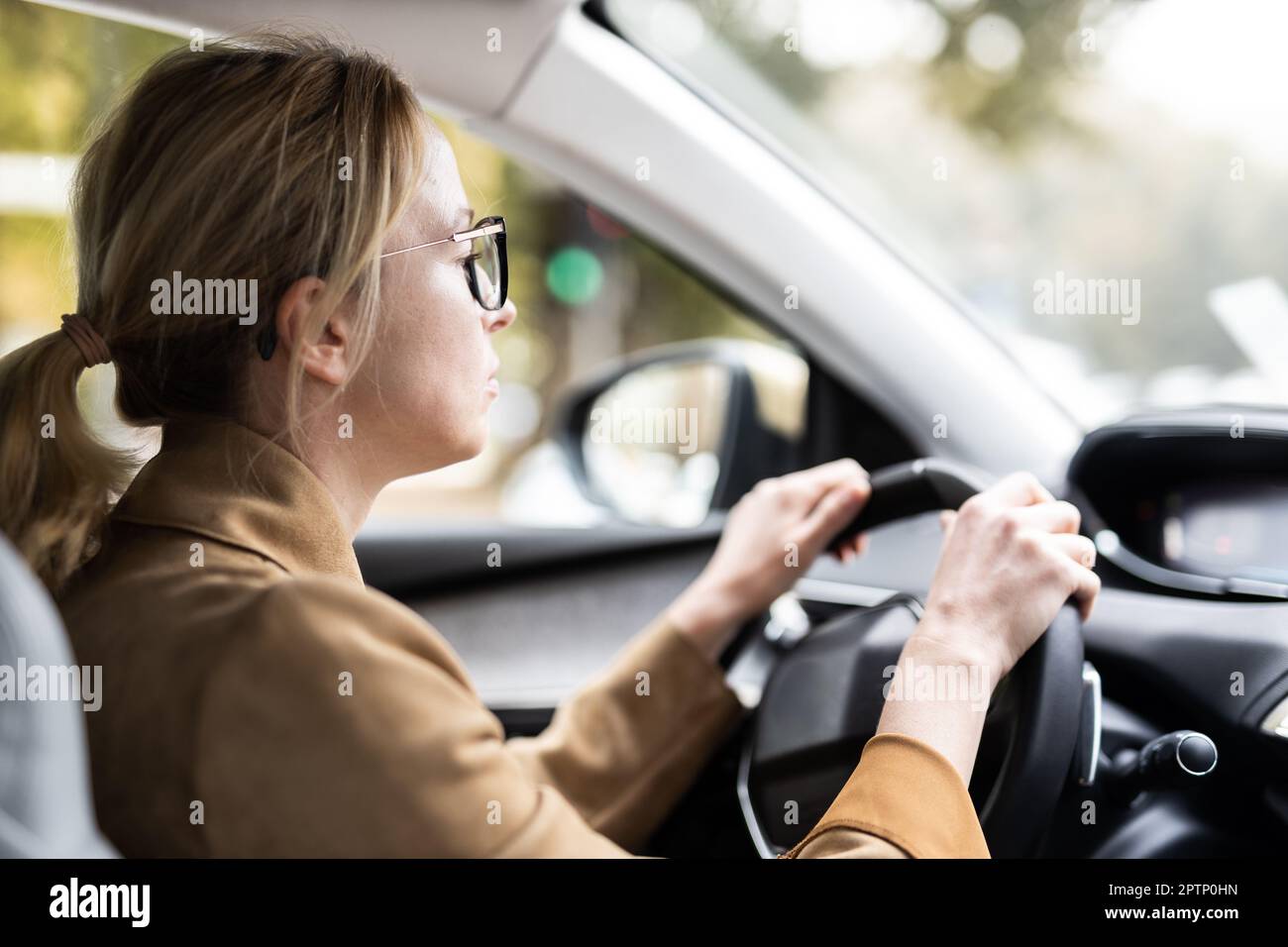 Business woman driving a car to work. Female driver steering car on the ...