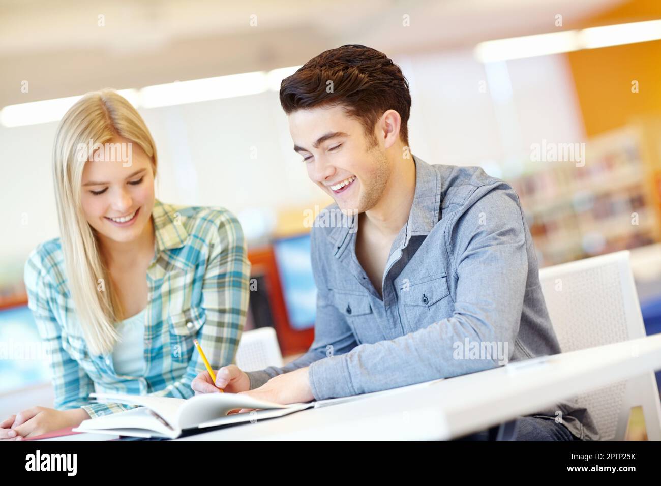 Working hard together. Two smiling students helping each other with ...