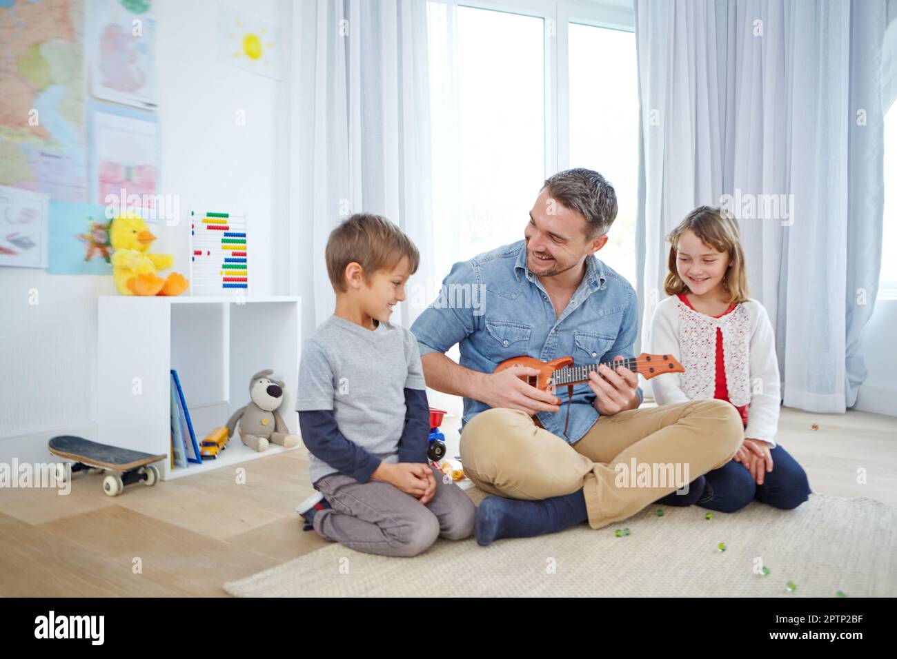 Adding some fun to their day. a happy father playing the guitar for his ...