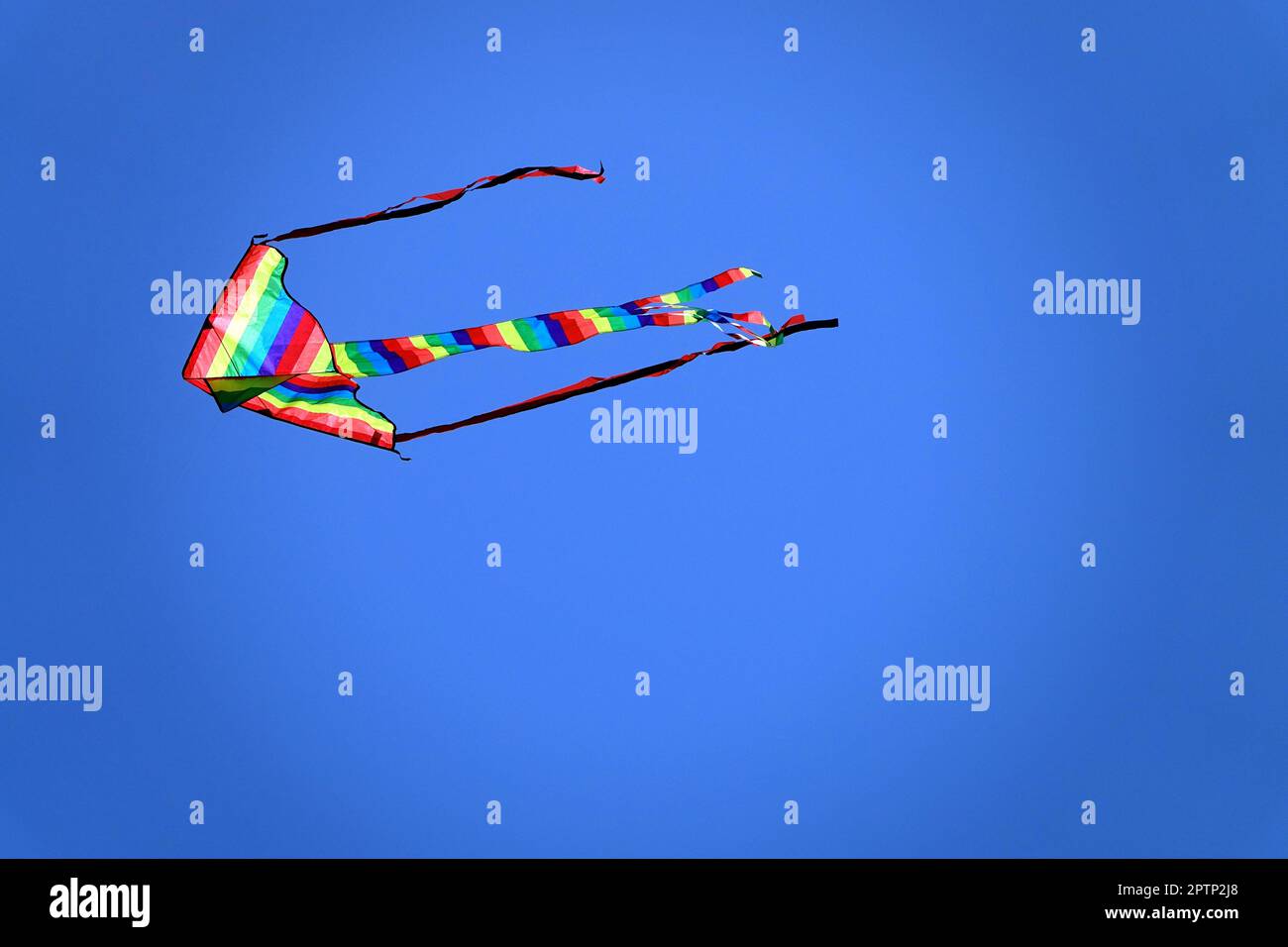 A single multicolor rainbow color handmade DIY kite flies isolated in ...