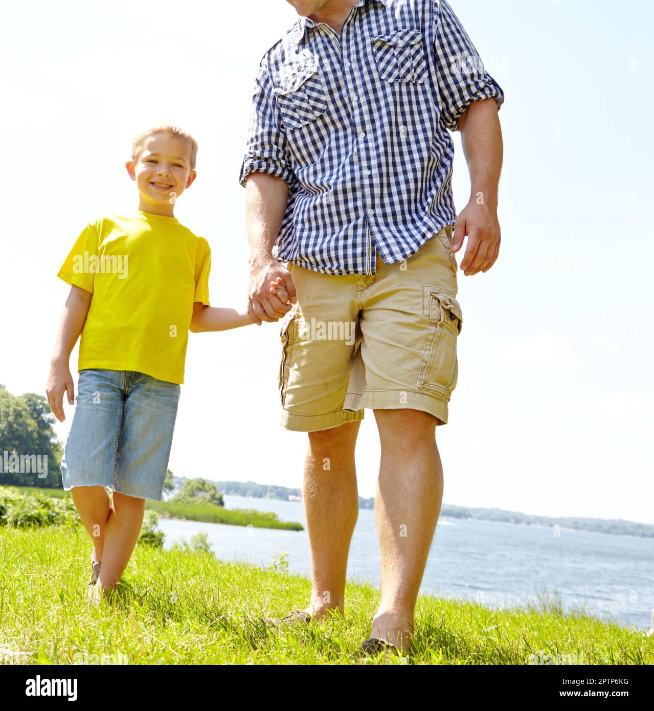So happy to be spending time with dad. Cute son walking with his dad by the lake and holding his ...