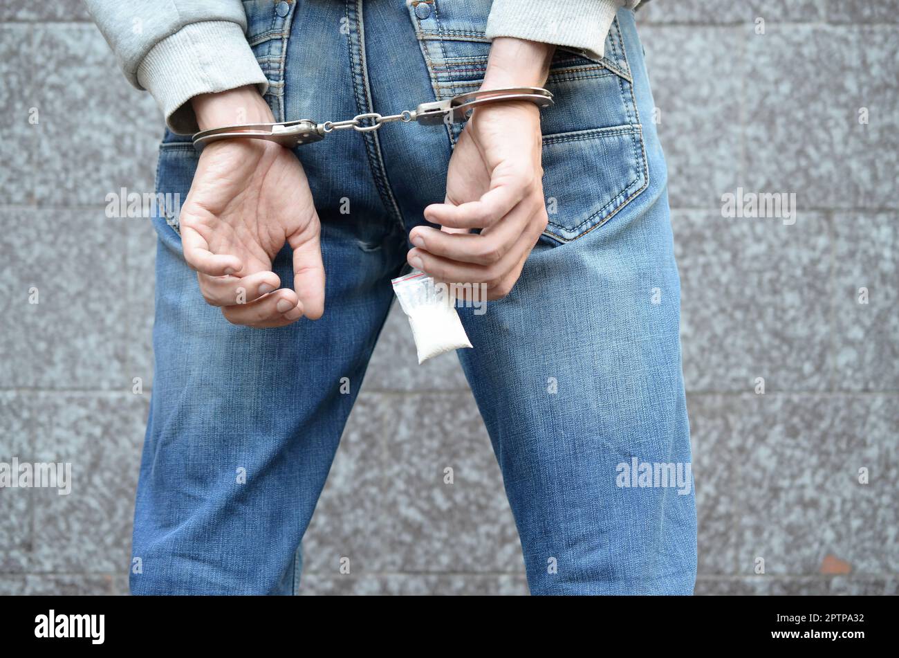 Arrested drug dealer in handcuffs with small heroin drug package on ...