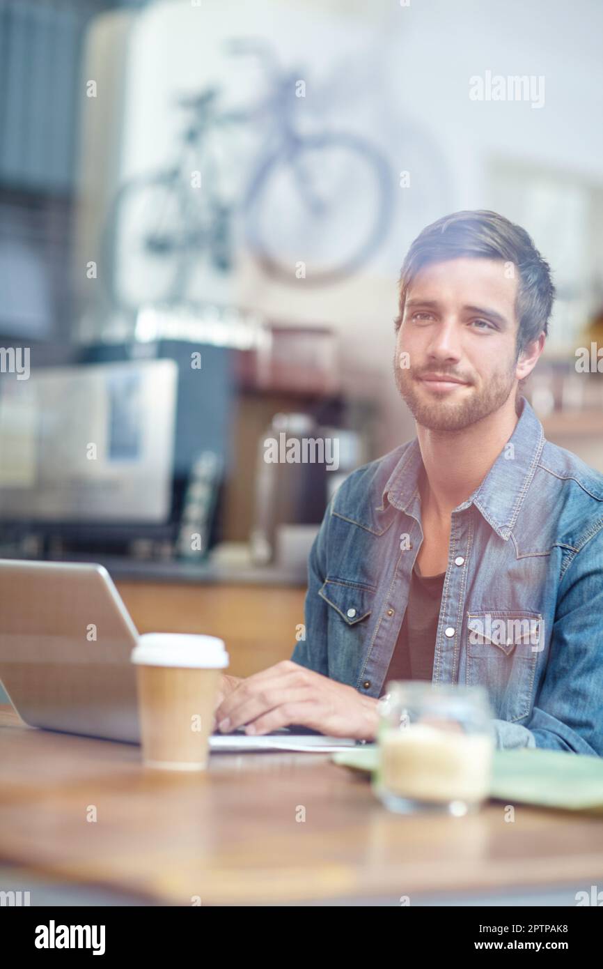Coffee culture. a handsome young man sitting with his laptop in a ...