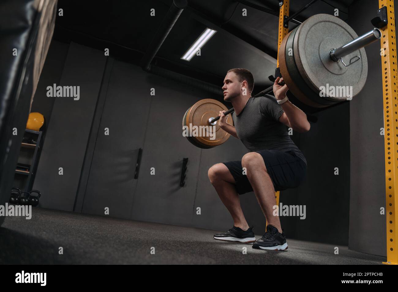 Muscular caucasian man lifting weights and doing back squat in gym ...