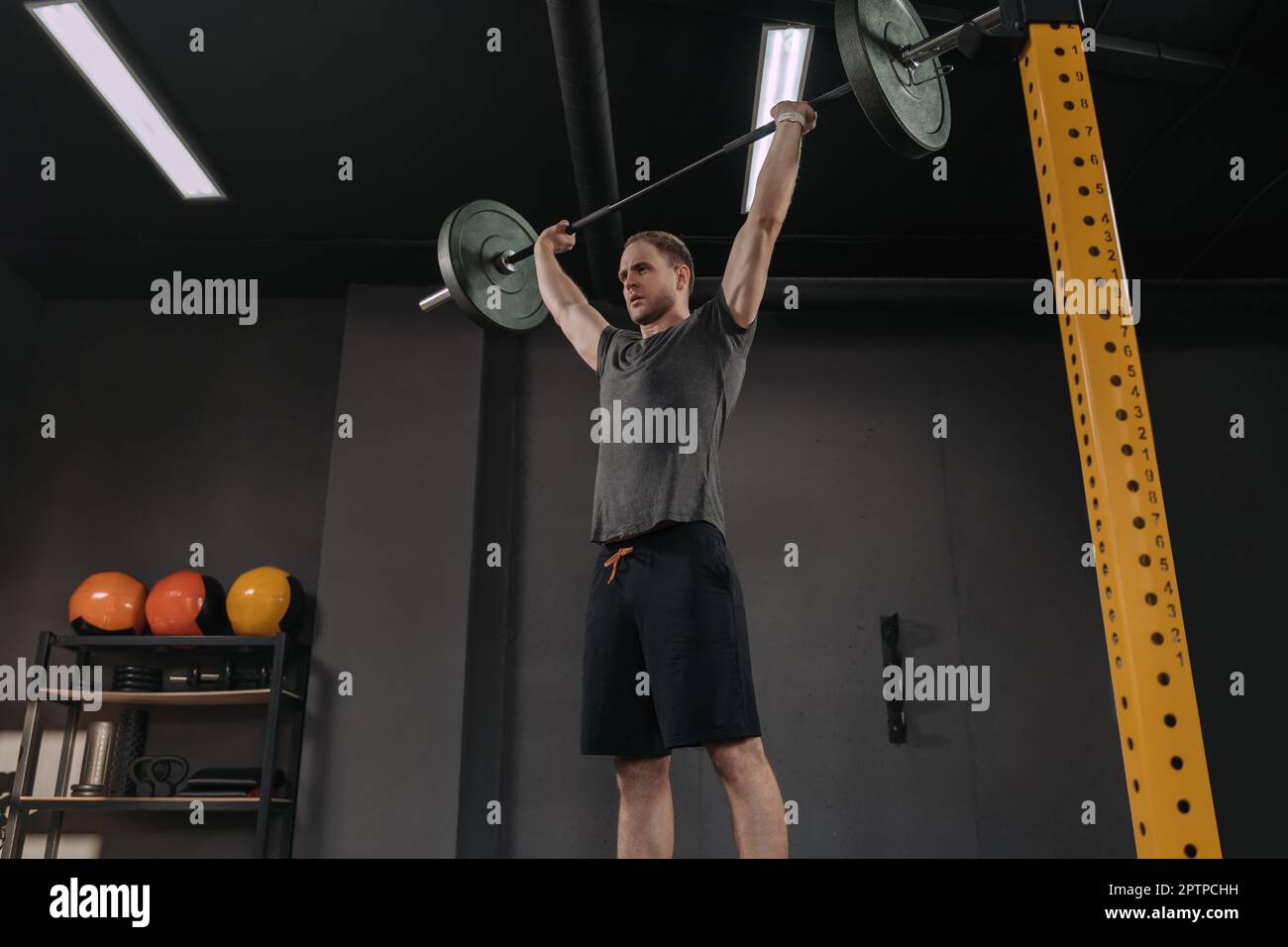 Crossfit athlete doing overhead squat with barbell. Portrait of young ...