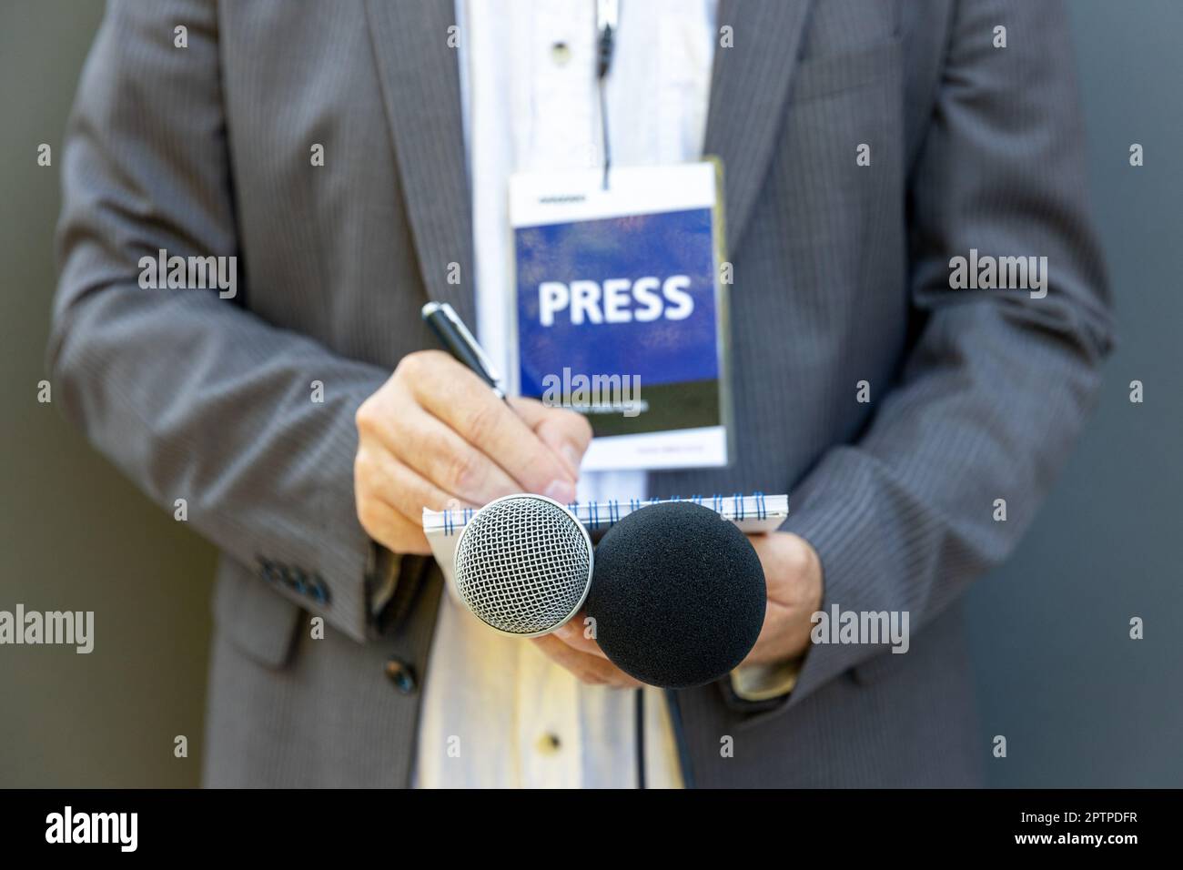 Male reporter at press conference or media event, writing notes ...