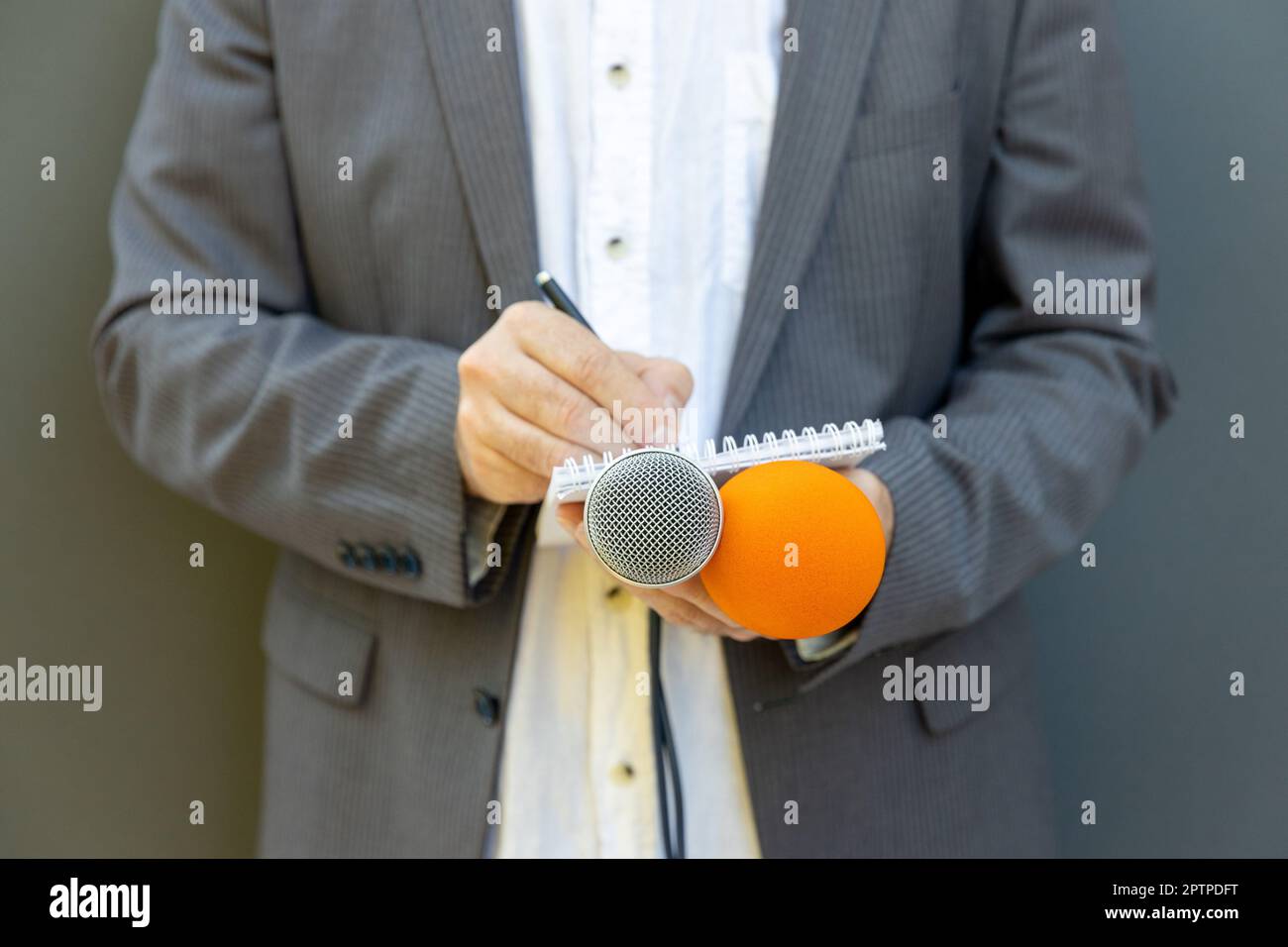 Male reporter at press conference or media event, writing notes ...