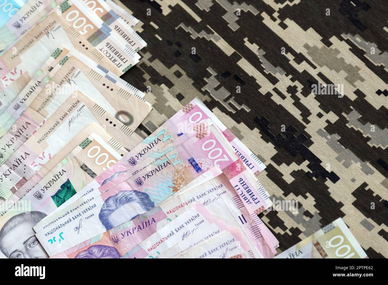 Ukrainian hryvnya bills on fabric with texture of Ukrainian military ...
