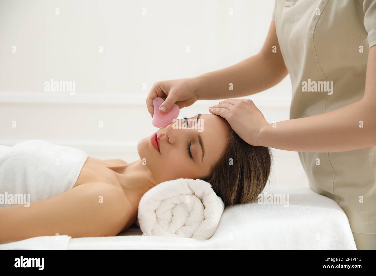 Young woman receiving facial massage with gua sha tool in beauty salon Stock Photo - Alamy