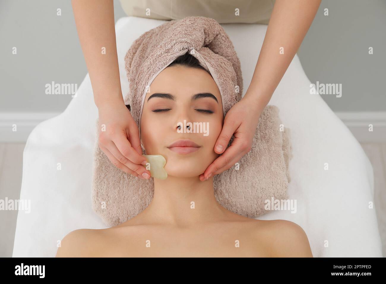 Young woman receiving facial massage with gua sha tool in beauty salon, top view Stock Photo - Alamy