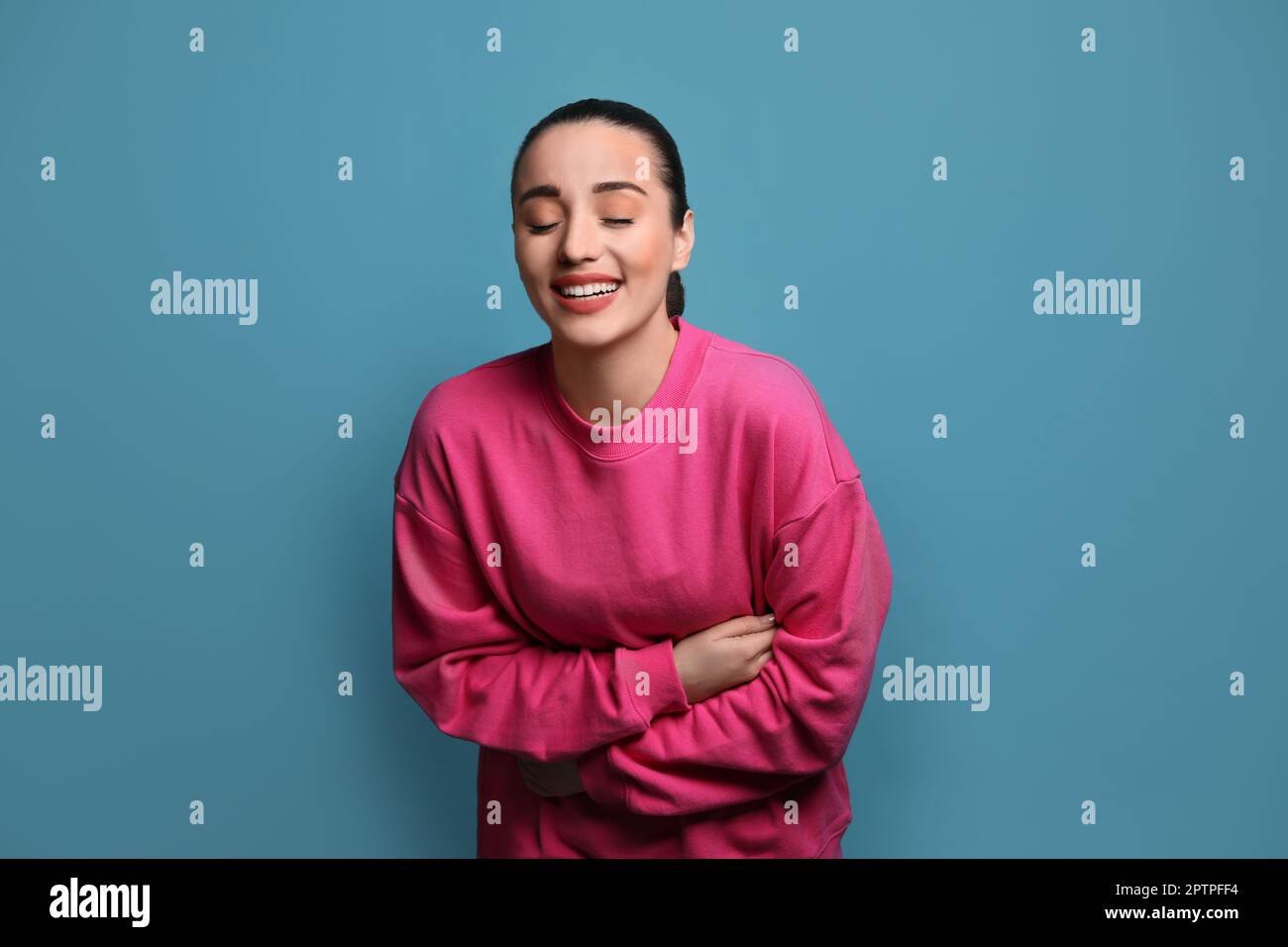 Beautiful young woman laughing on light blue background. Funny joke ...