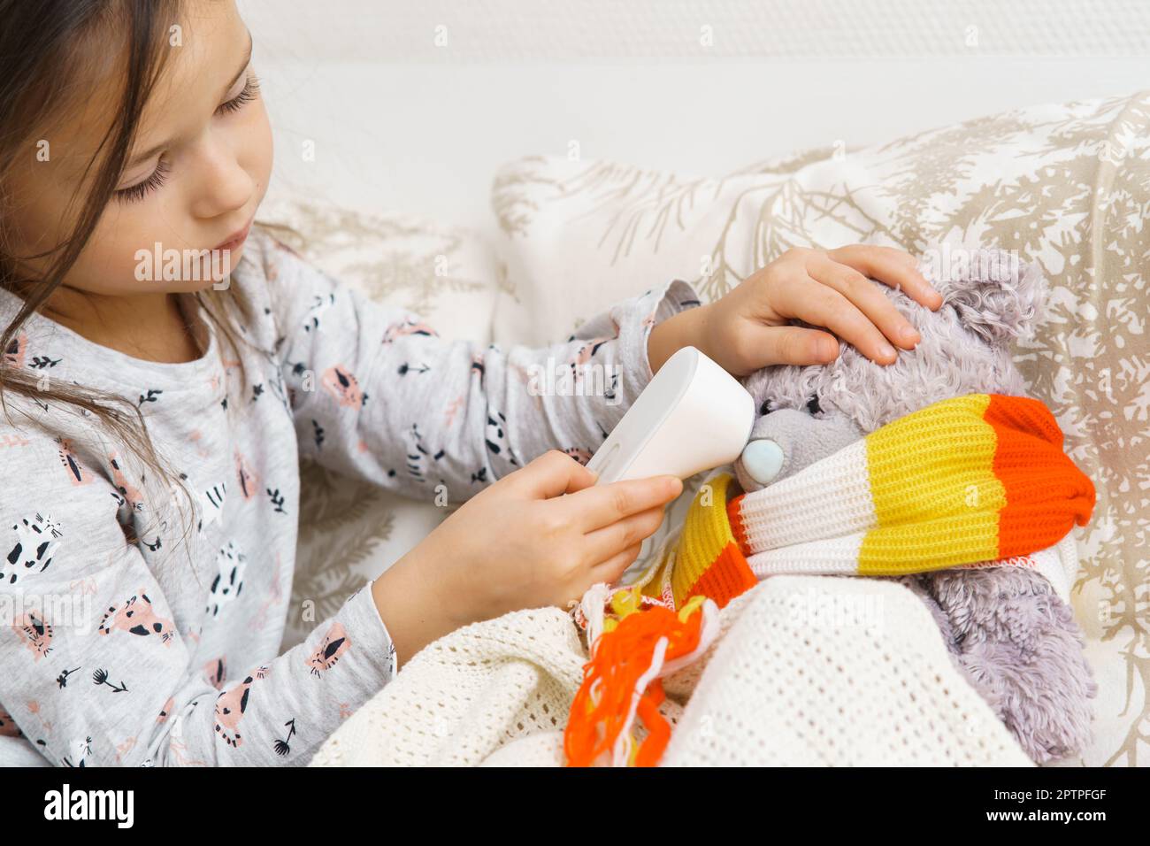 Concentrated child, girl healing bear toy, examining temperature with ...
