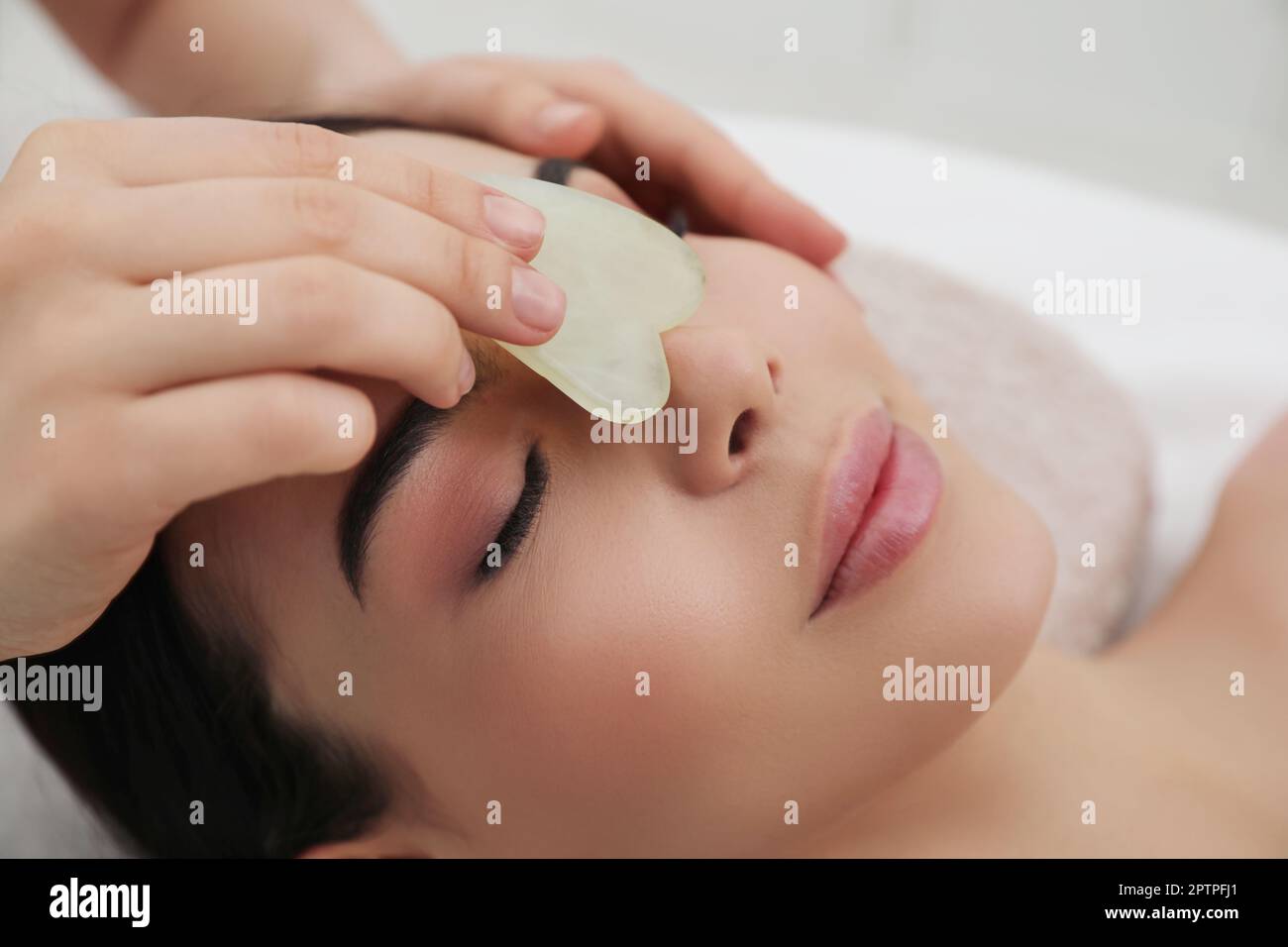 Young woman receiving facial massage with gua sha tool in beauty salon, closeup Stock Photo - Alamy