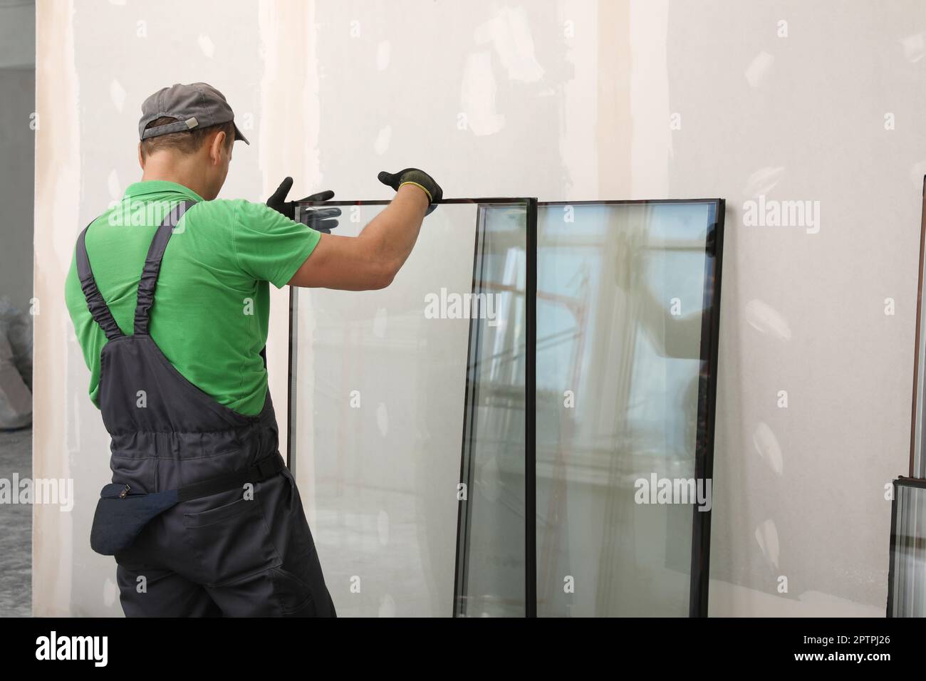 Worker in uniform preparing double glazing window for installation ...