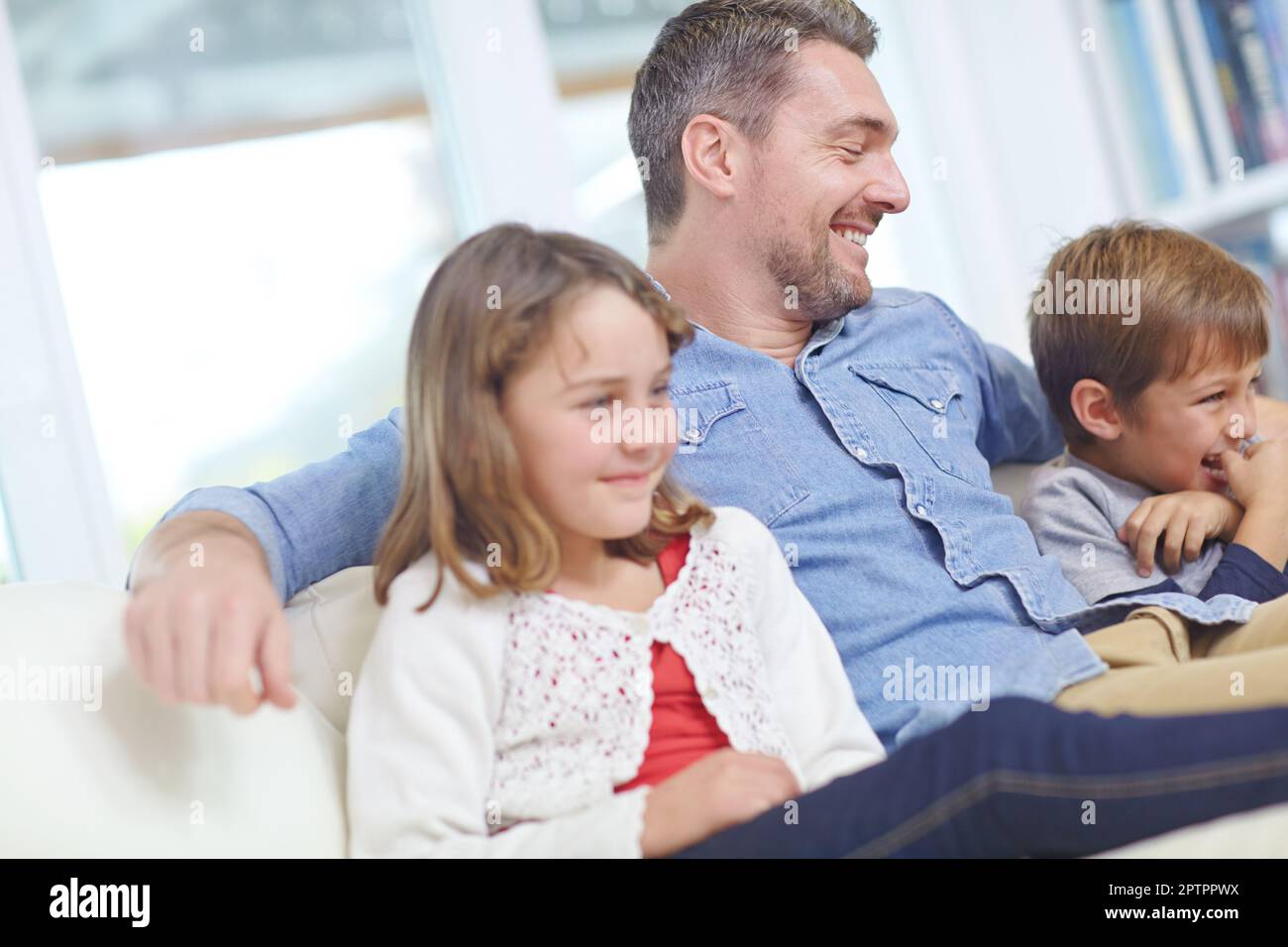 His kids mean the world to him. of a happy father relaxing on the sofa ...