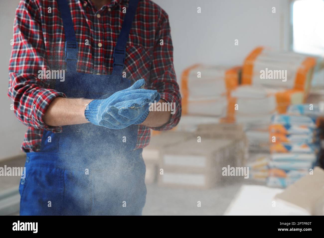 Construction worker shaking off dust from hands in room prepared for ...