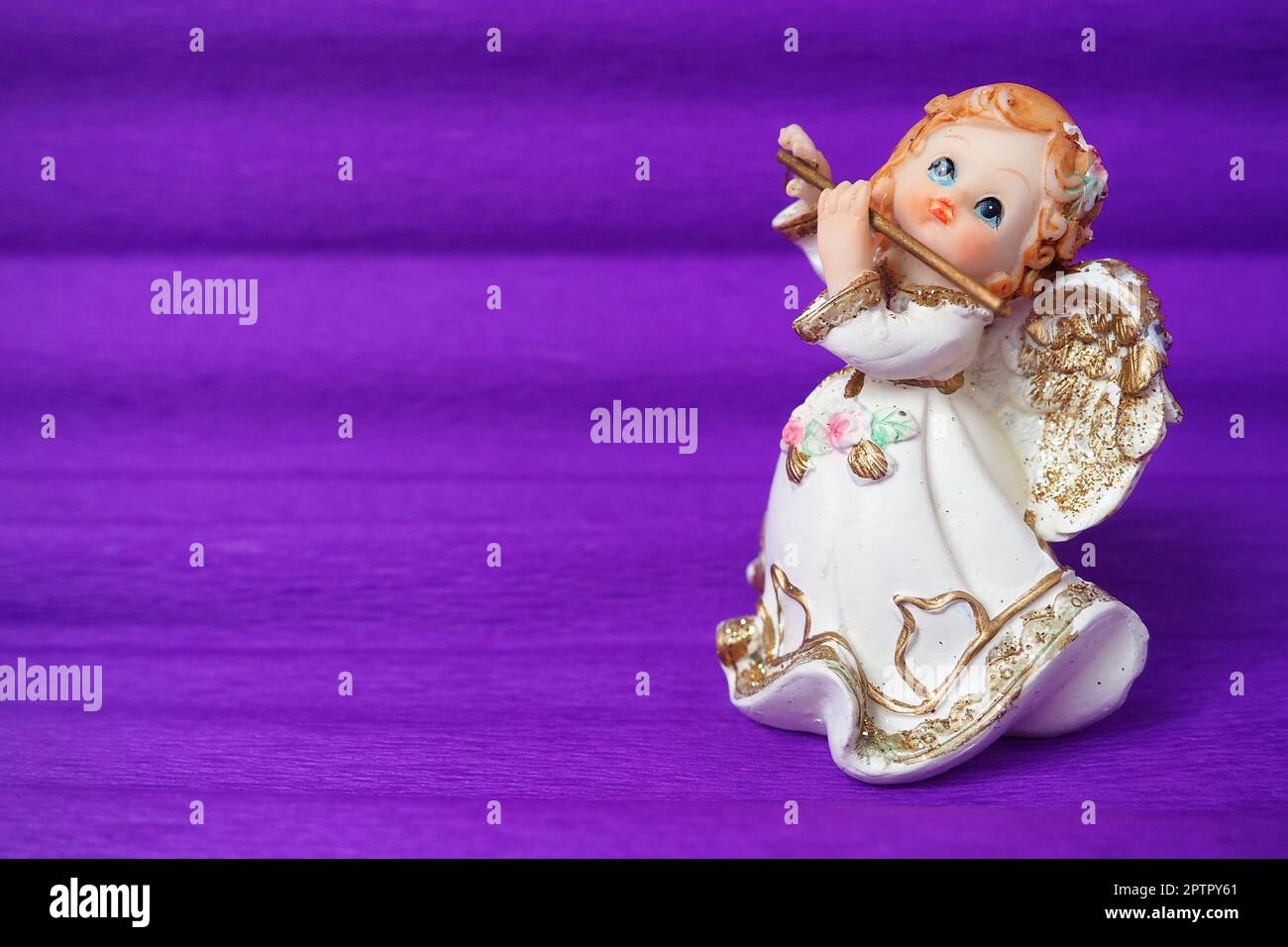 Guardian angel plays the flute. Figurine of a red-haired girl in a ...