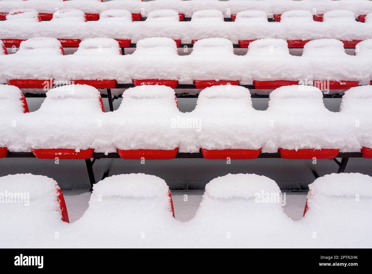 Empty outdoor football soccer stadium seats covered with snow in winter ...