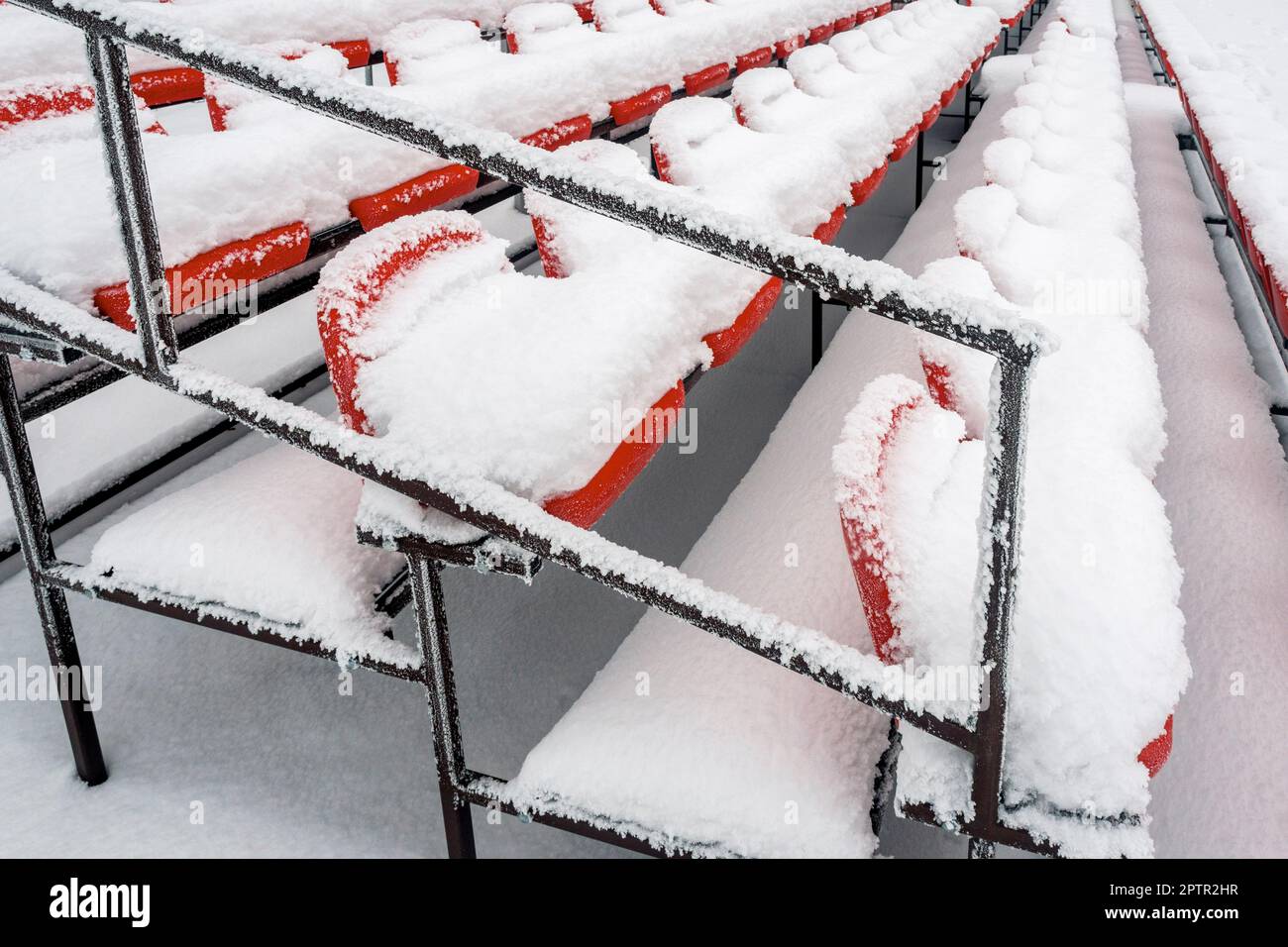 Empty outdoor football soccer stadium seats covered with snow in winter ...