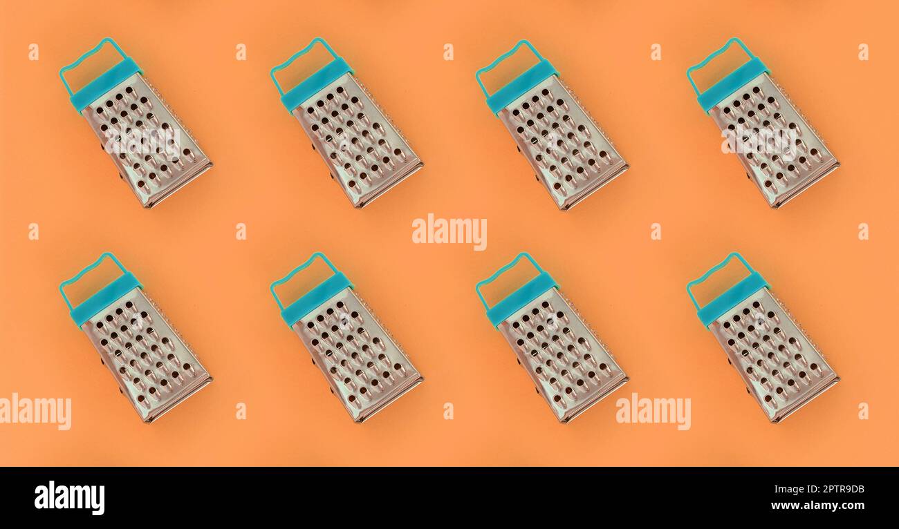 Small stainless steel graters lies on a pastel colored paper. Kitchen ...