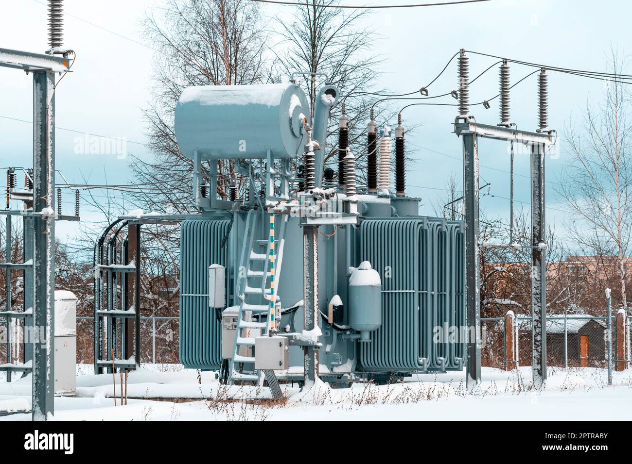 High voltage electrical transformer at a power plant in winter in the ...