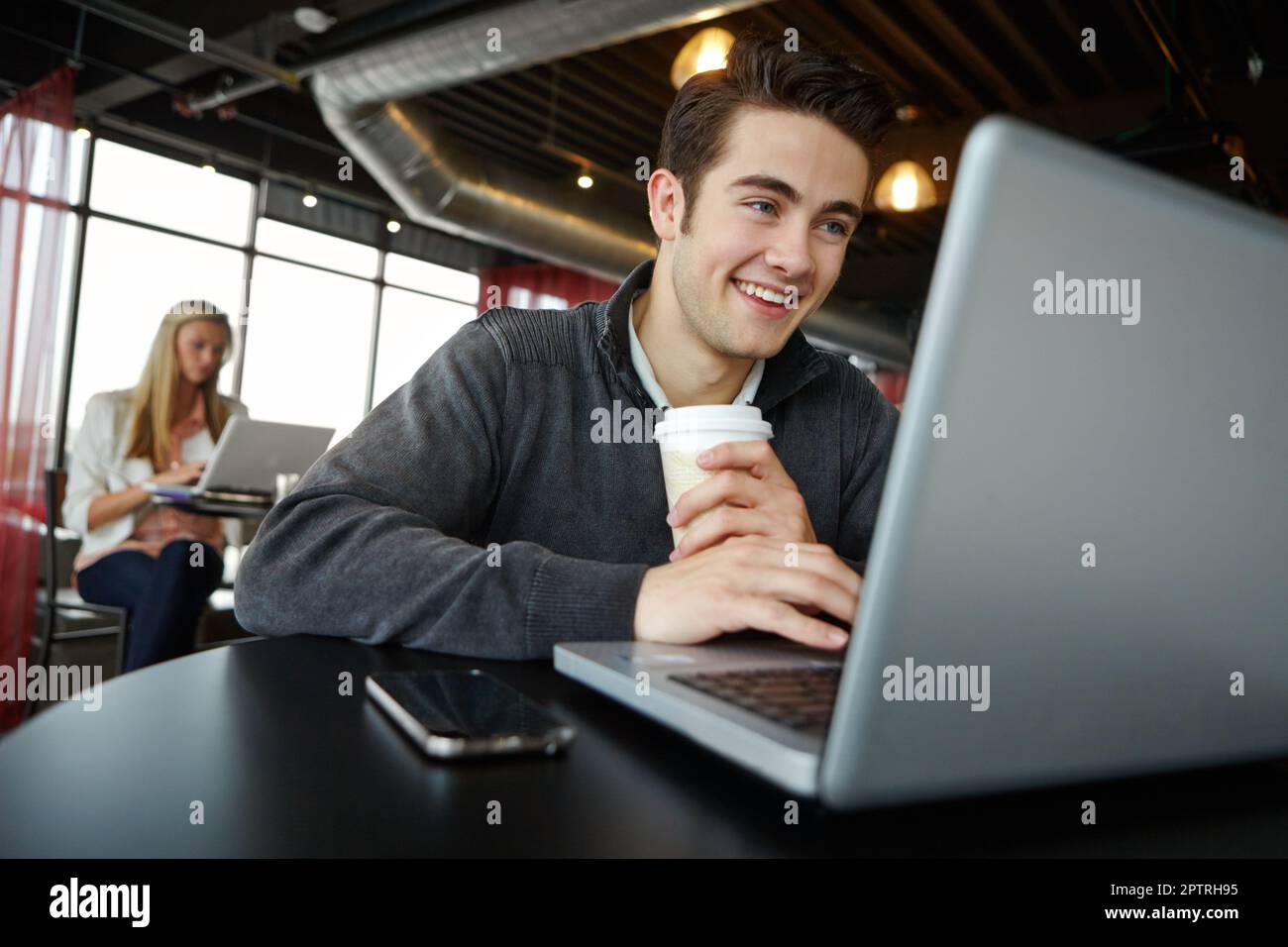 Checking his emails. A handsome young man using his laptop in a coffee ...