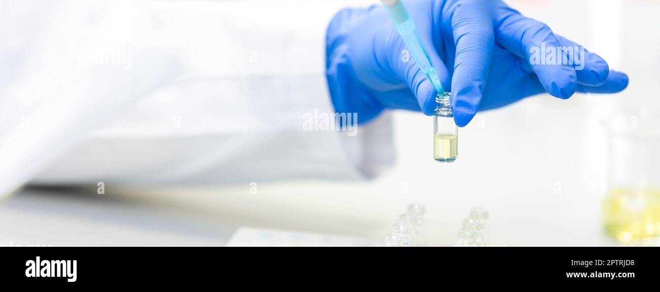 Female researcher with dropper dripping liquid into a test tube in ...