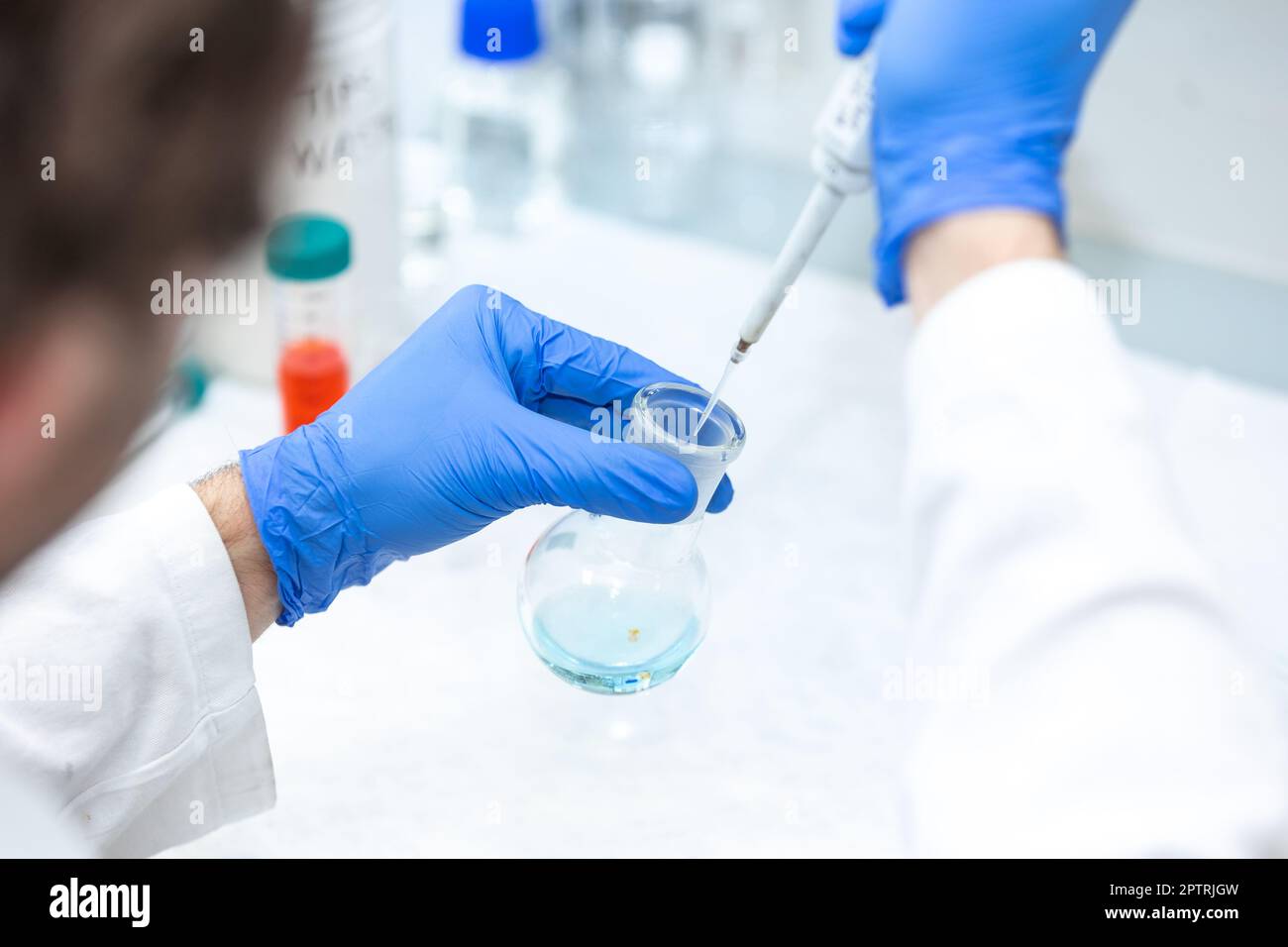 Female researcher with dropper dripping liquid into a test tube in ...