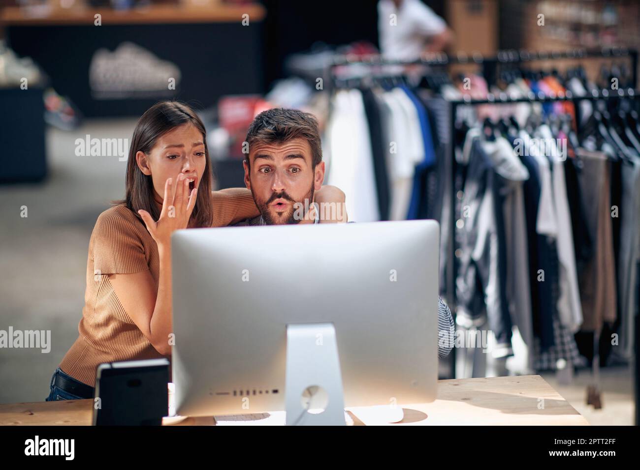 Young man and woman in front of computer desktop looking at screen ...