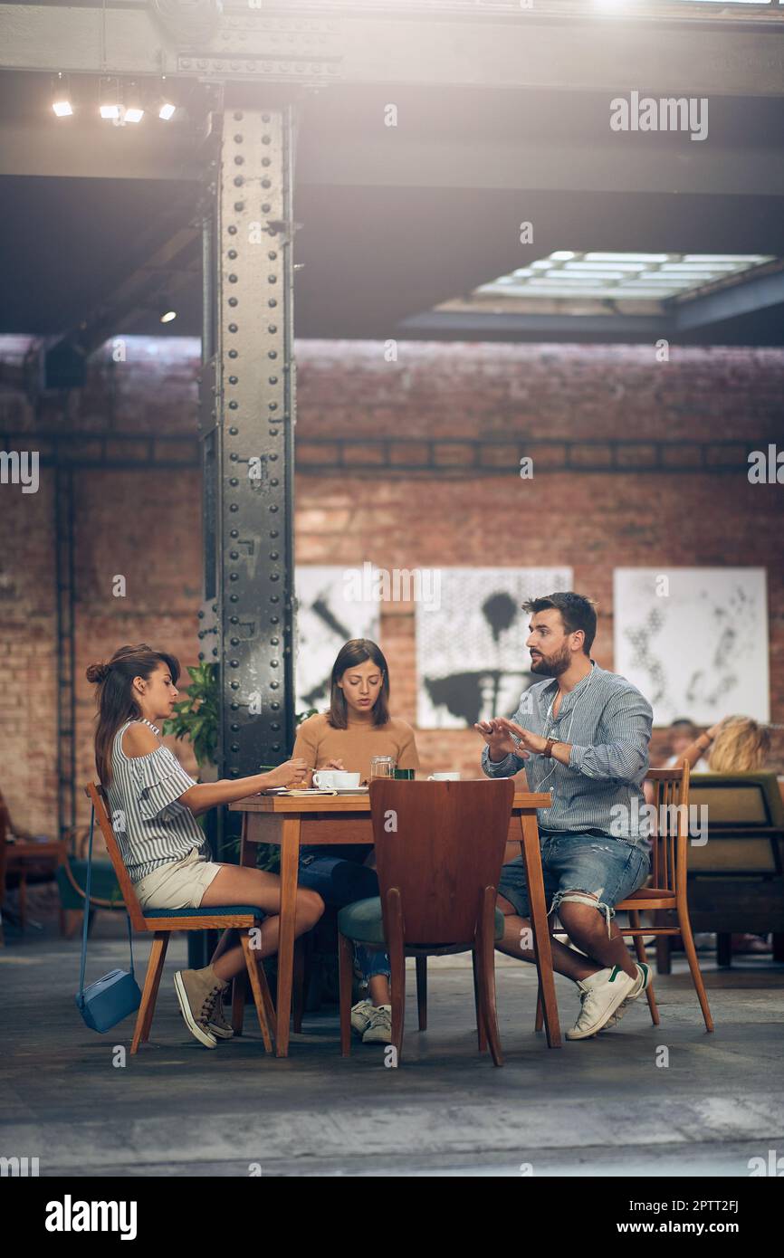Young group of friends at cafe, having coffee and talking. Young adults ...