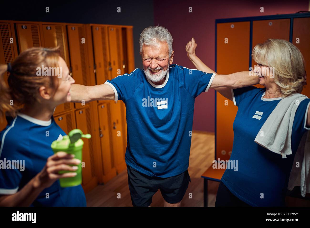 Sports team of seniors and young woman feeling joyful in locker room ...