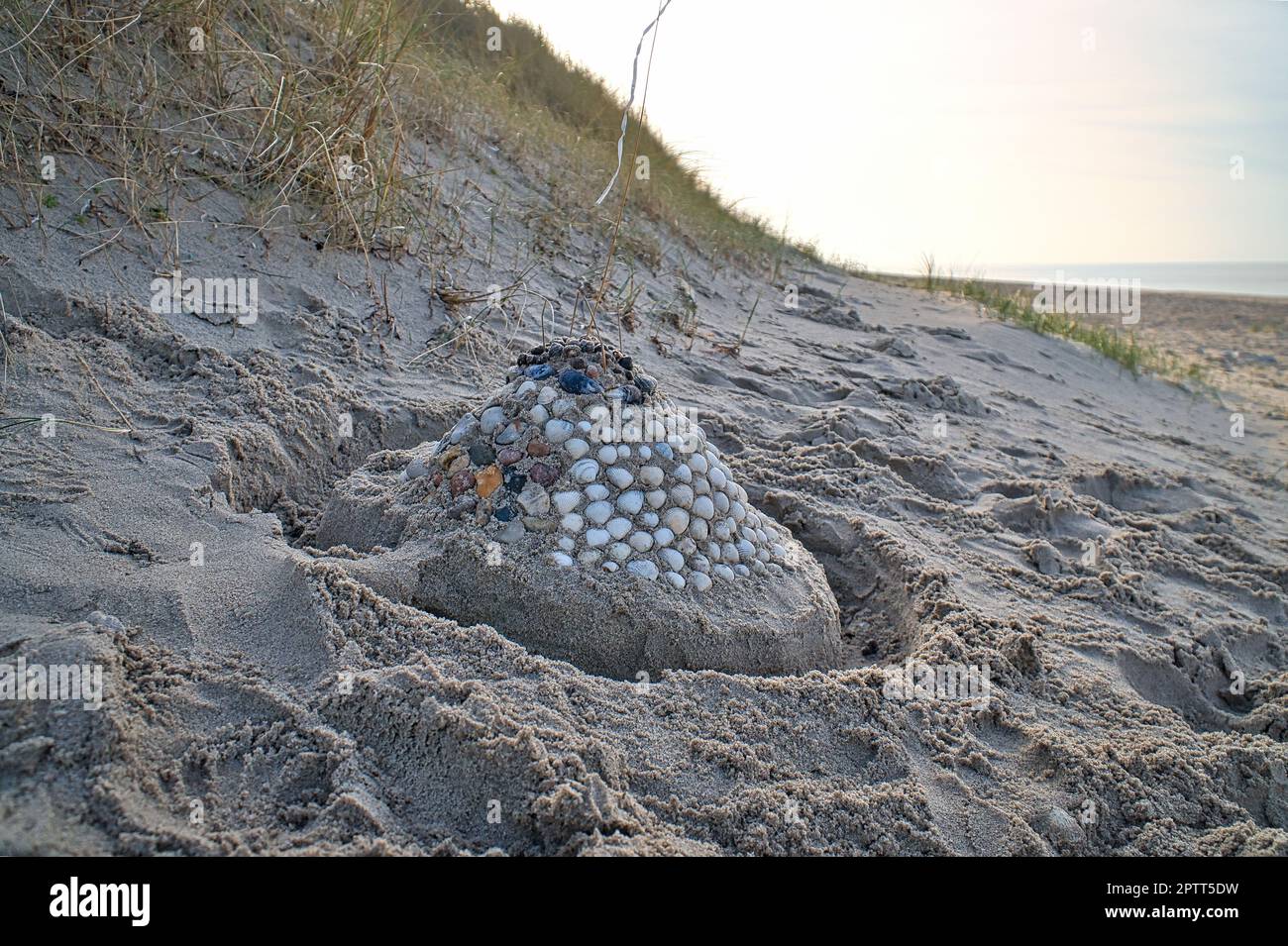 Sand castle with shells and sand. Moat around the castle in front of ...