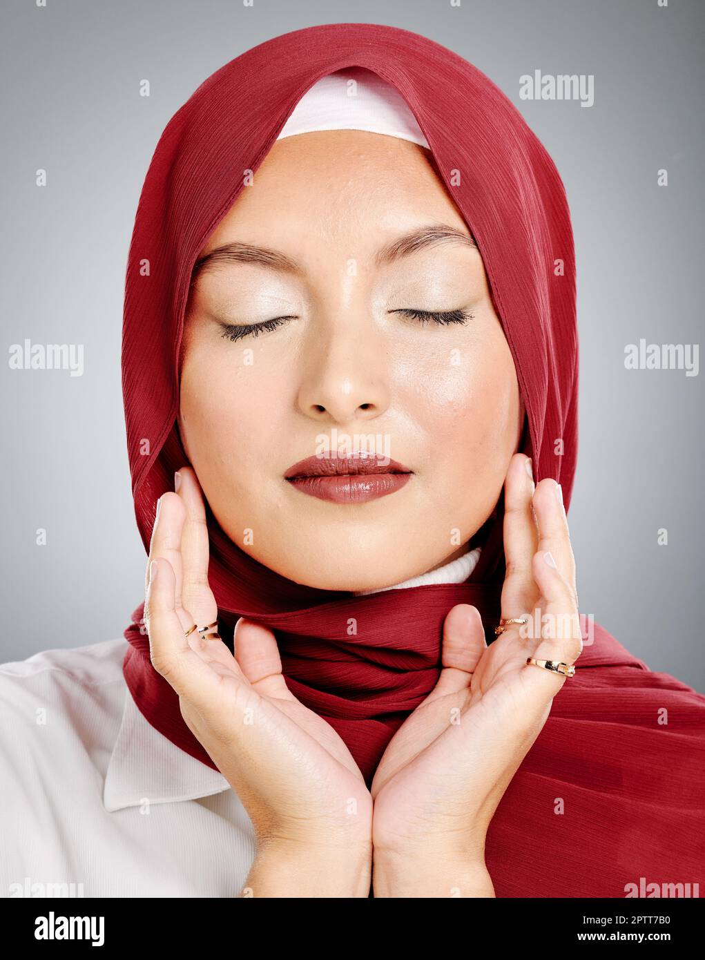 One beautiful young muslim woman with eyes closed wearing red headscarf and lipstick against ...