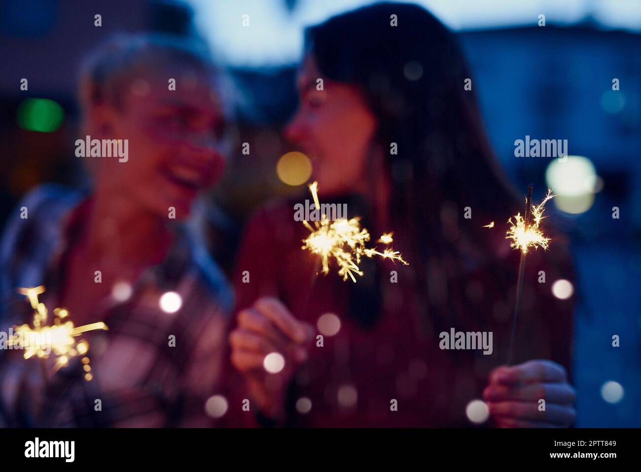 Two happy women blurred playing with fireworks on holiday together ...