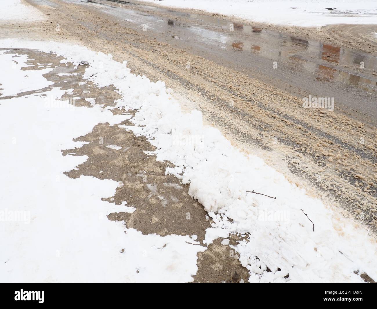 Roadside with a snowdrift. Difficult driving conditions. Wet slippery ...