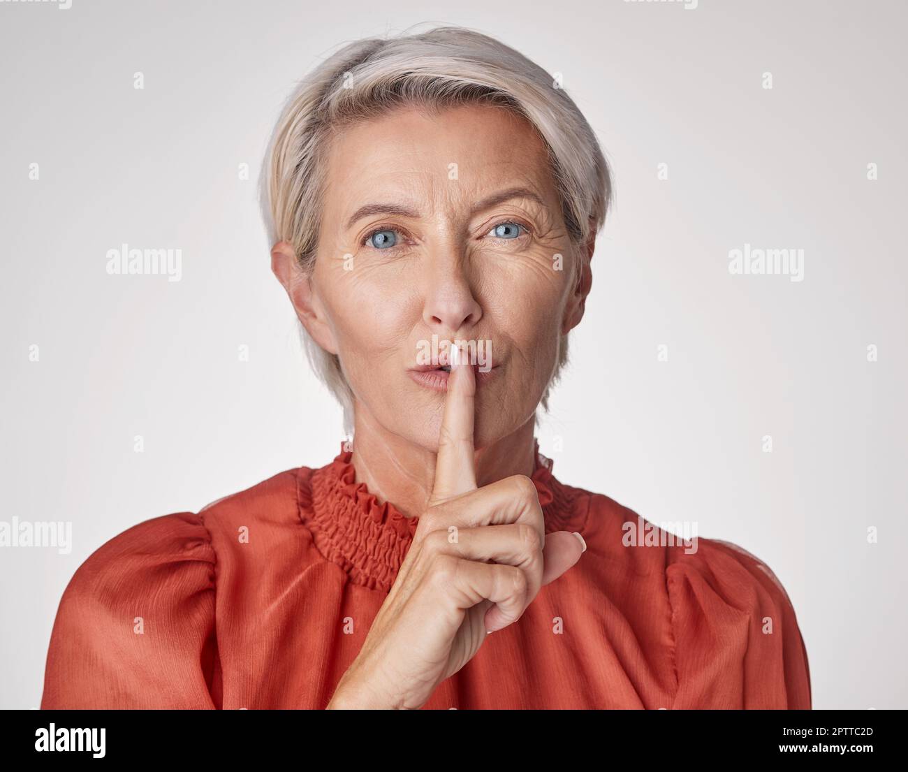 One mature caucasian woman gesturing with a finger on her lips to be ...