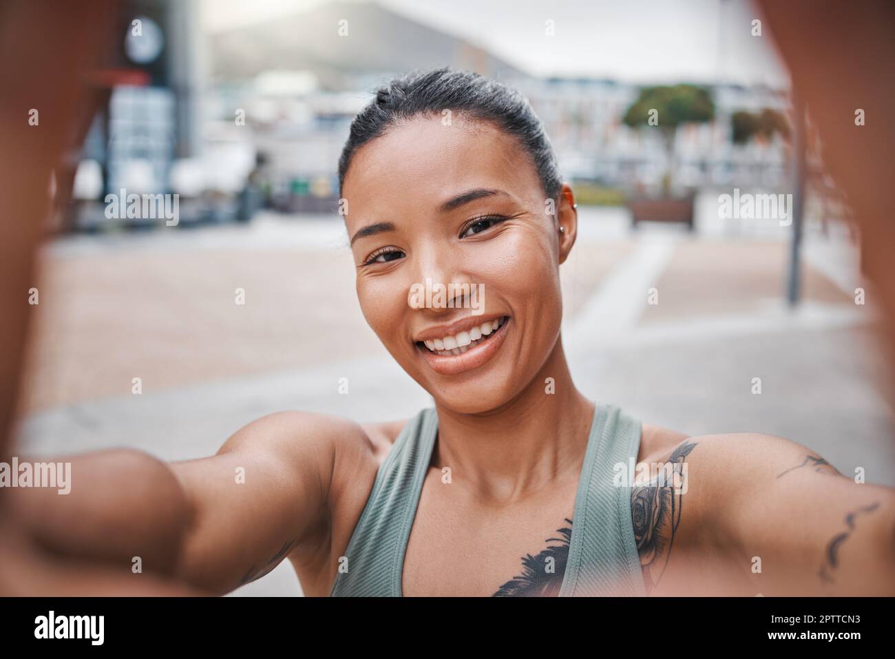 Sporty young mixed race woman with tattoos taking selfies while exercising. Happy young ...