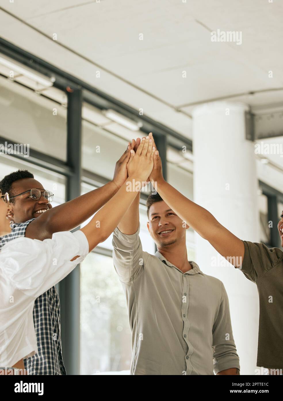 Smiling creative business team standing in office and giving high five ...