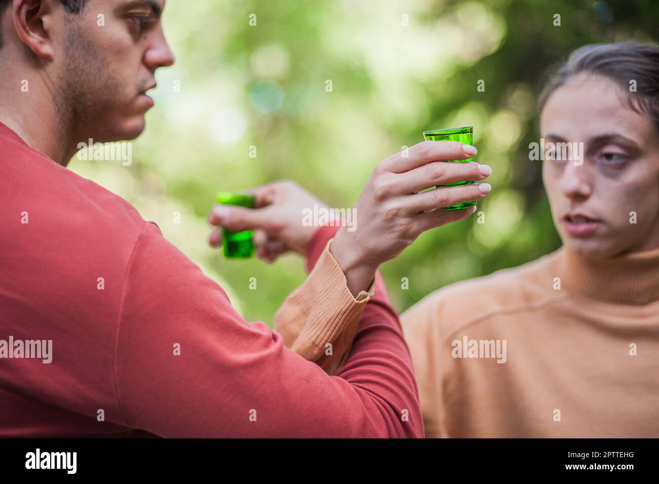 Cheers. Very drunk couple, a boy and a girl, chug shot drink from small ...