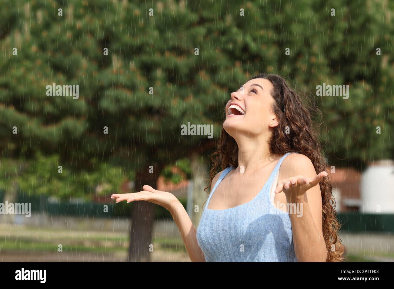 Excited woman under the sudden rain looking up Stock Photo - Alamy